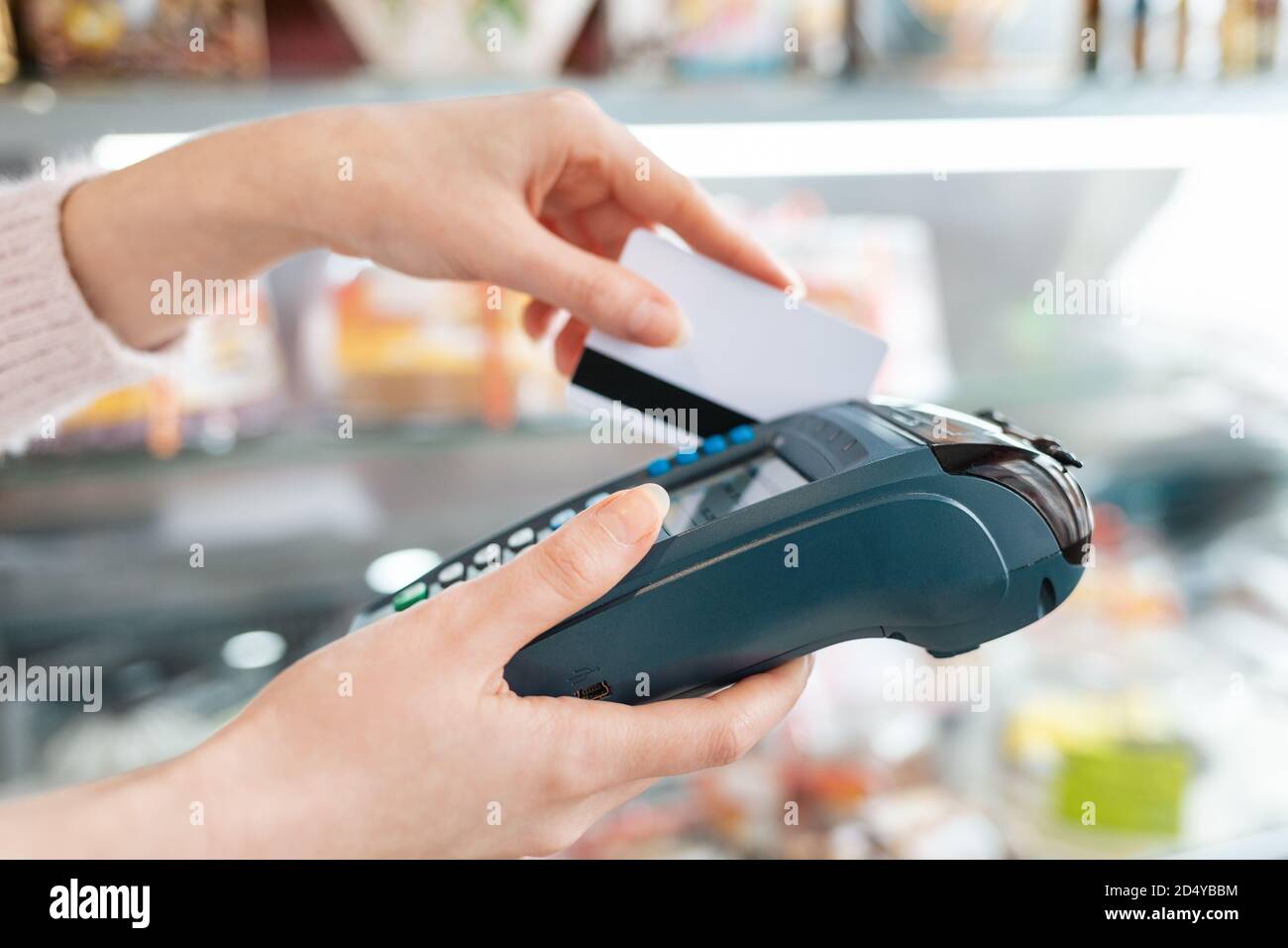 The woman swipes a Bank card through the payment machine to complete ...