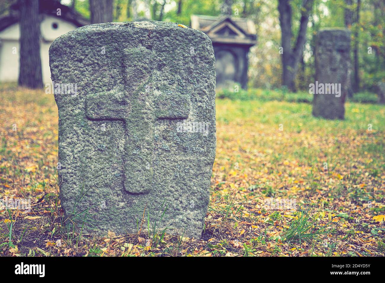 A worn sandstone grave marker in the shade on a very bright day. There ...