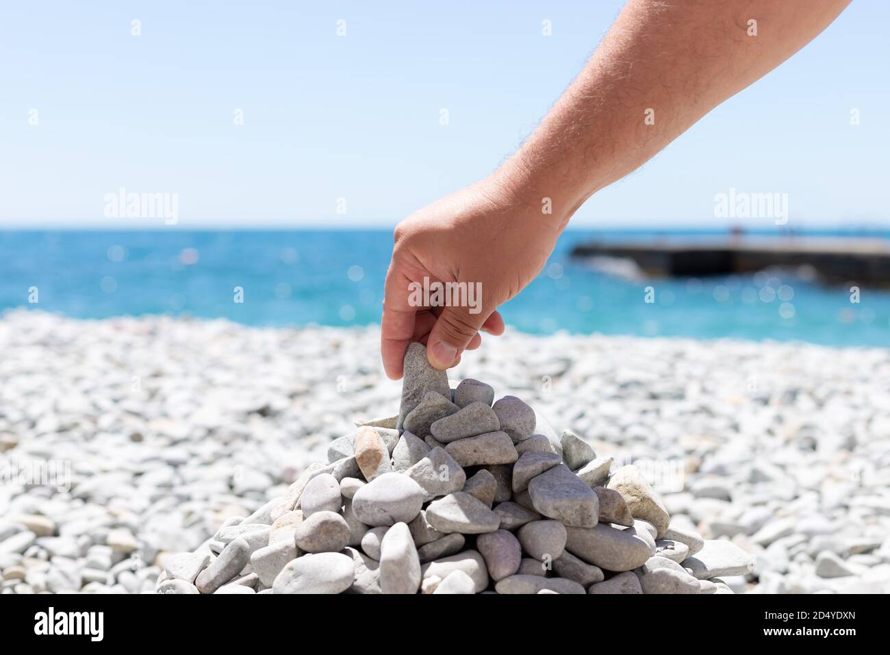 man's hand builds a pebble pyramid Stock Photo - Alamy