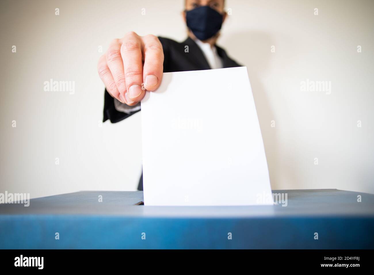 woman wearing mask putting vote in ballot Stock Photo - Alamy