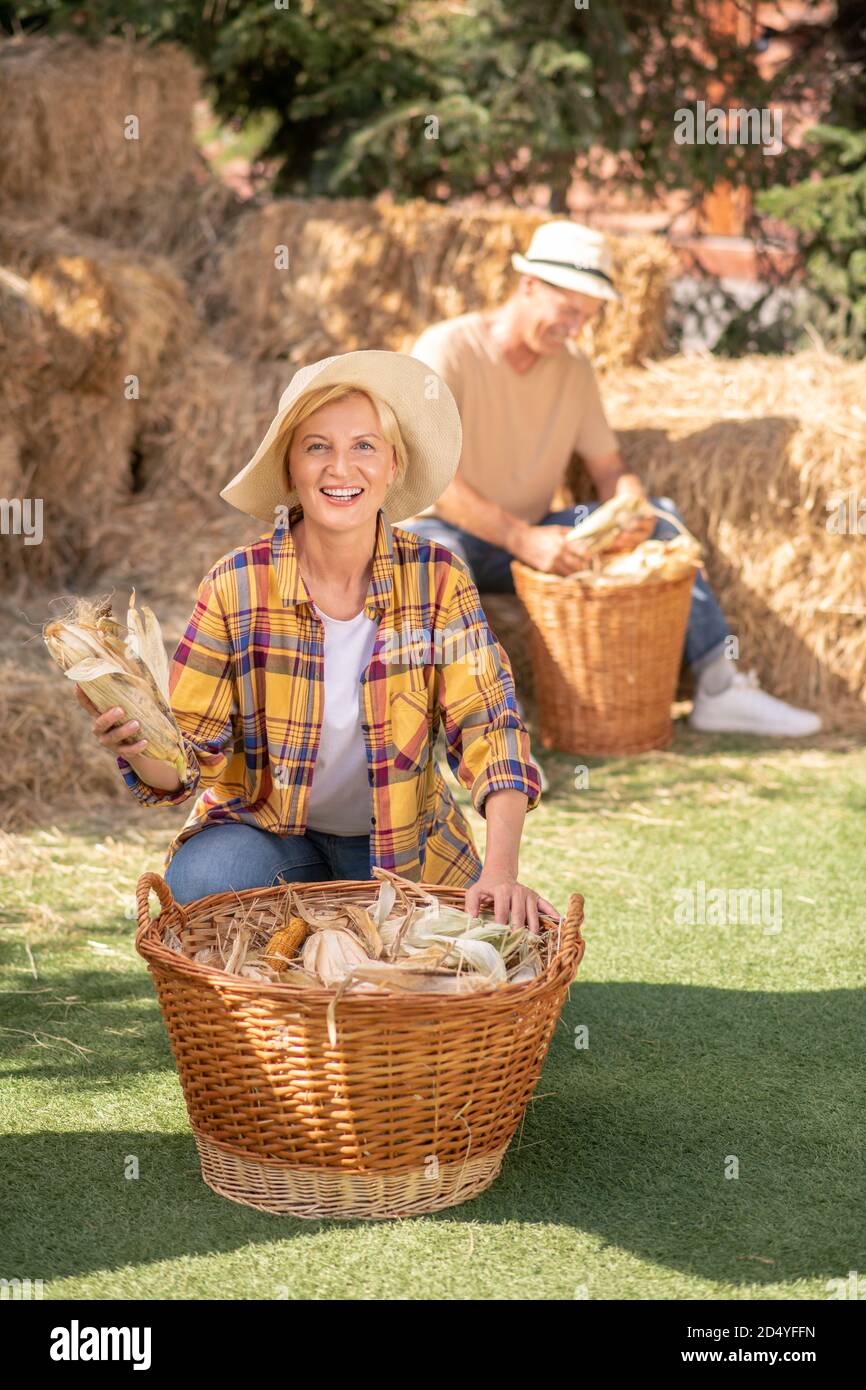 Female farmer holding cob, male farmer shucking cobs behind her Stock ...