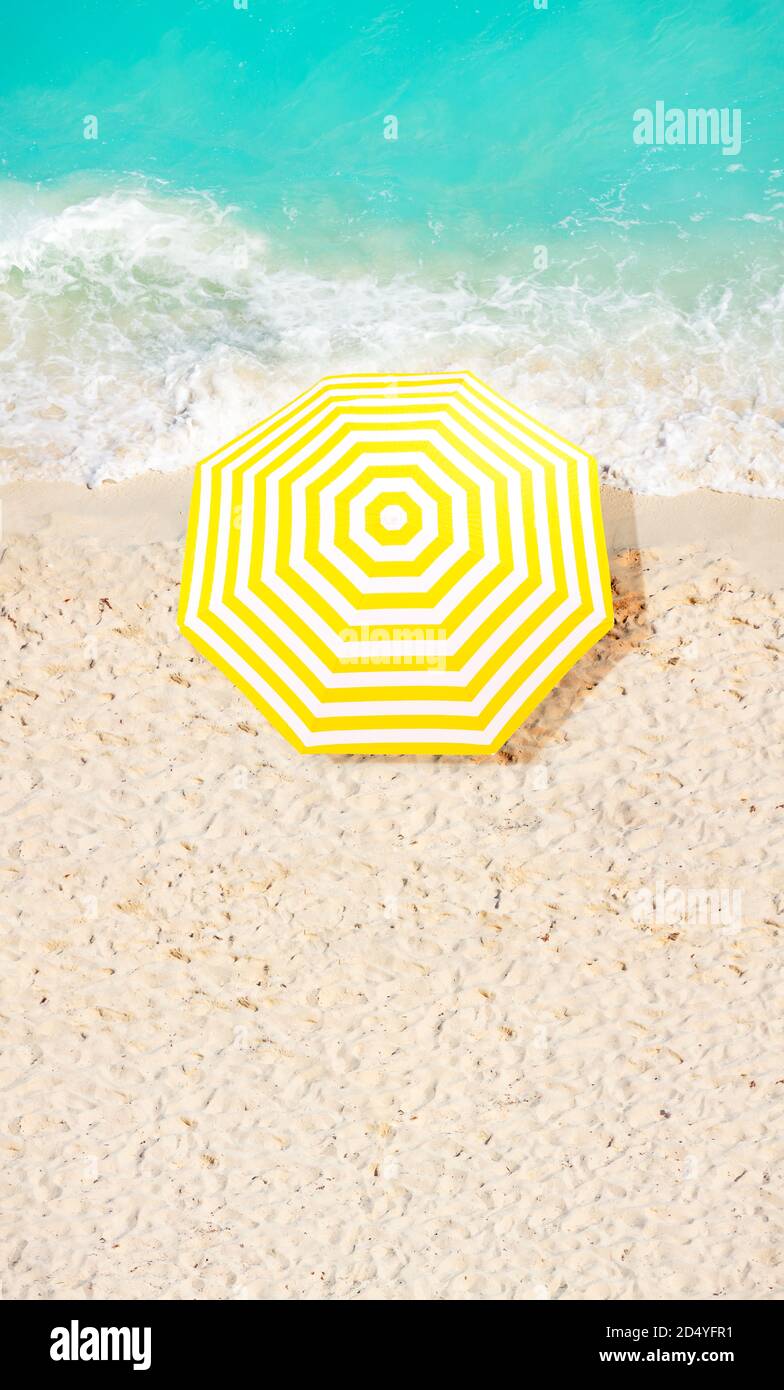 View from above of beach umbrella on the sand near ocean surf waves ...