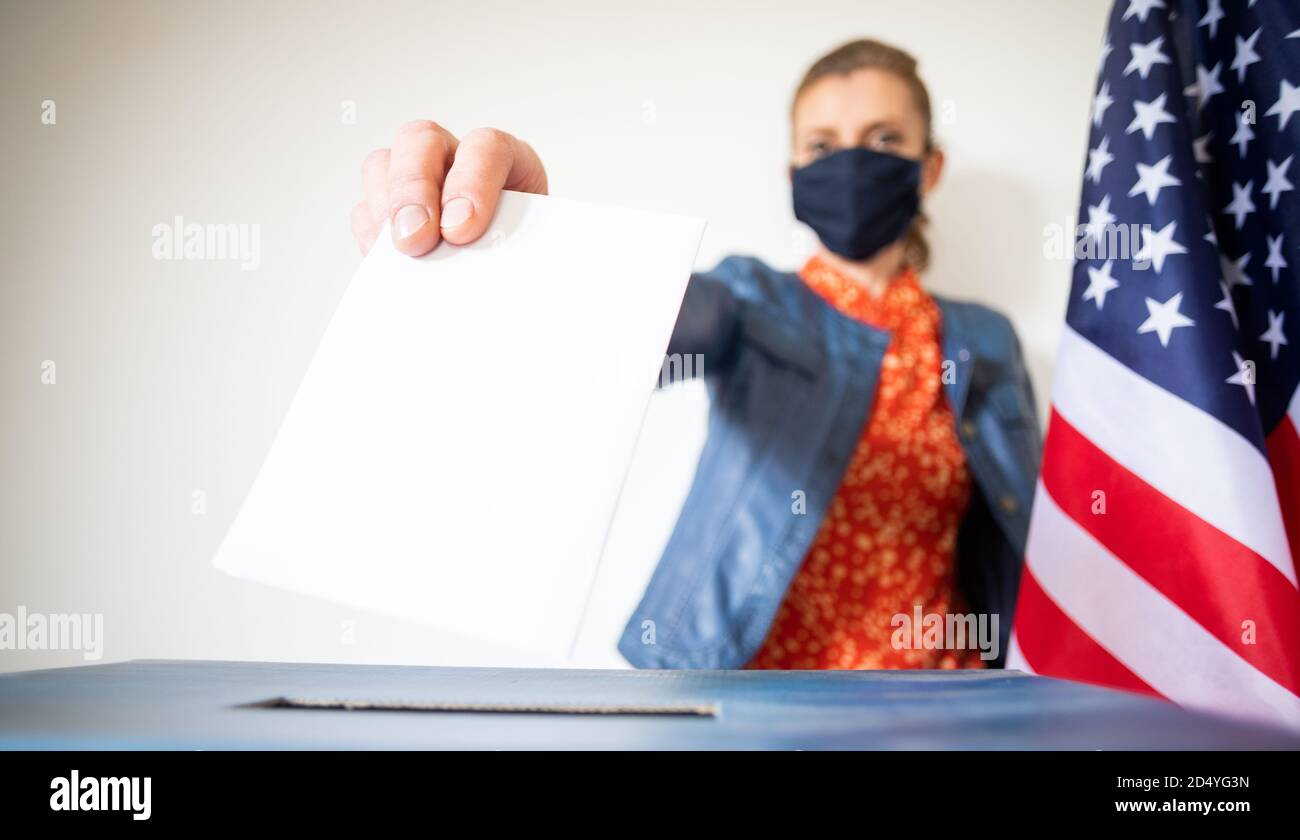 woman wearing mask putting vote in ballot Stock Photo - Alamy