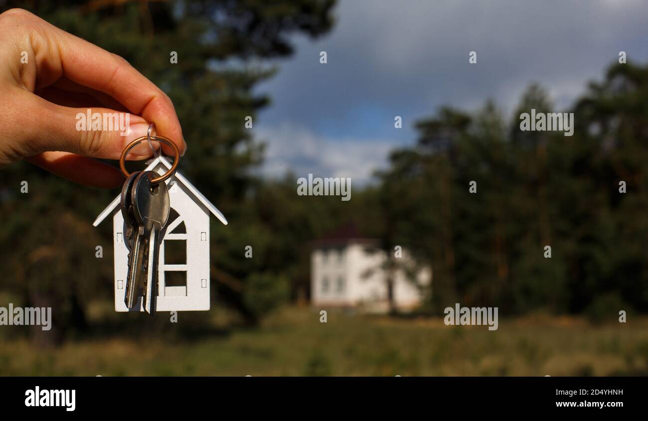Wooden key chain and keys in hand on the background of an unfinished ...