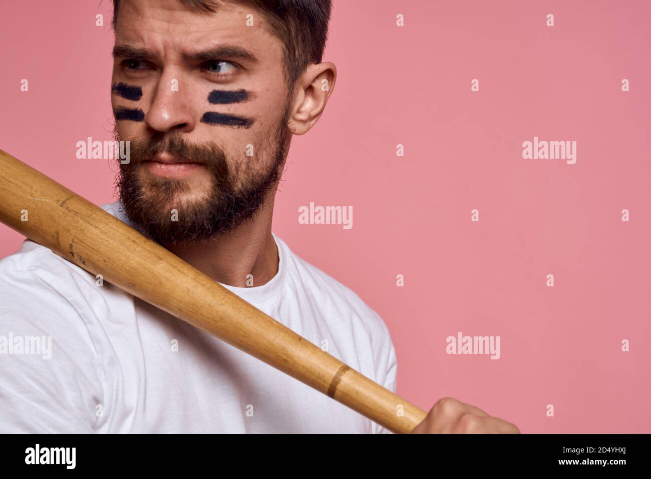 Emotional man with a baseball bat in his hand on a pink background and ...