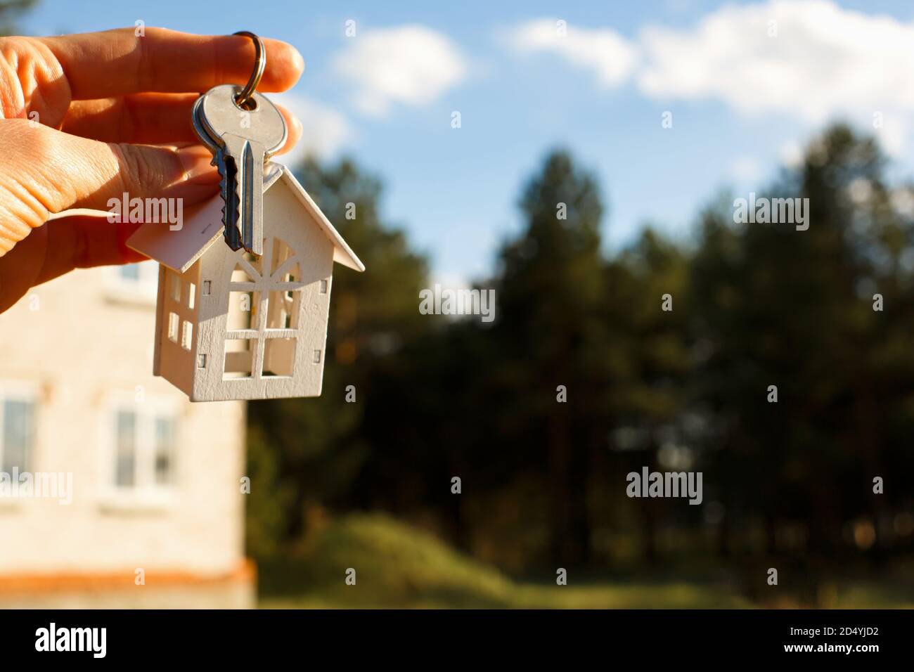 Wooden key chain and keys in hand on the background of an unfinished ...