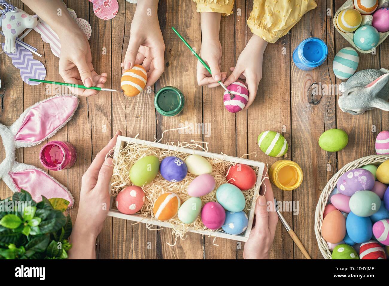 A mother, father and their child painting eggs. Happy family preparing ...