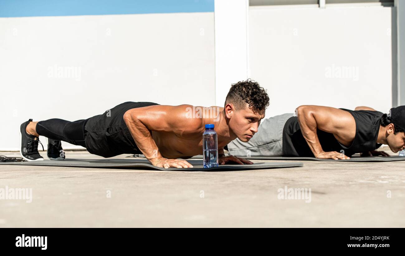 Group of fit male bodybuilders doing bodyweight push up exercise ...