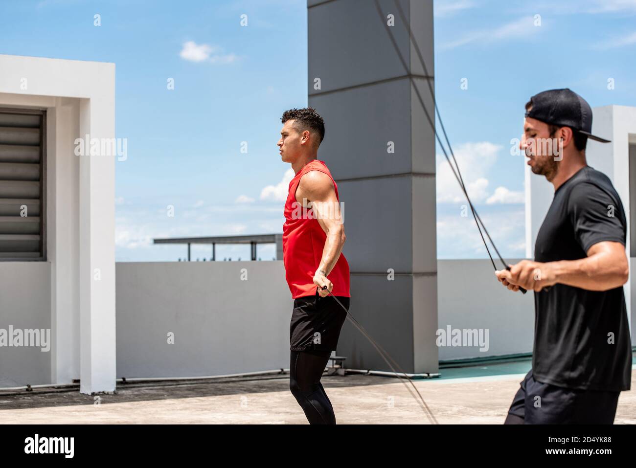 Two handsome Caucasian sportsmen doing outdoor jump rope exercise on ...