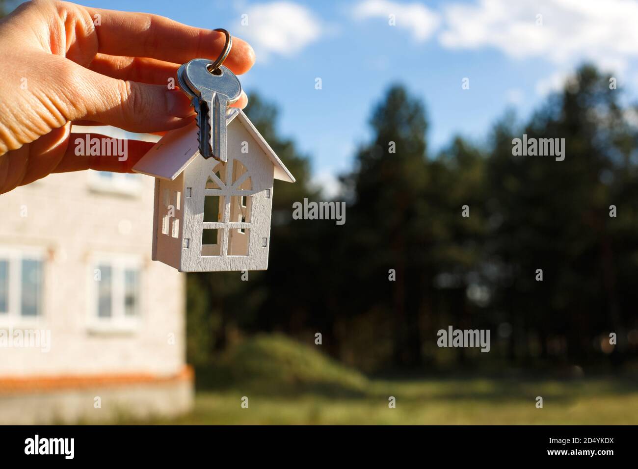 Wooden key chain and keys in hand on the background of an unfinished ...