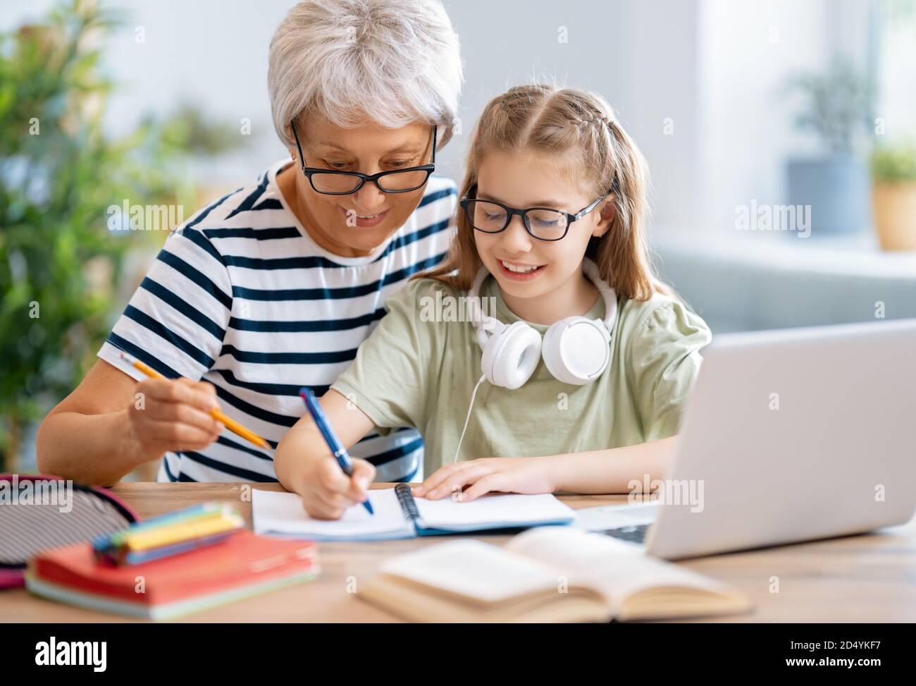 Back to school. Happy child and adult are sitting at desk. Girl doing ...