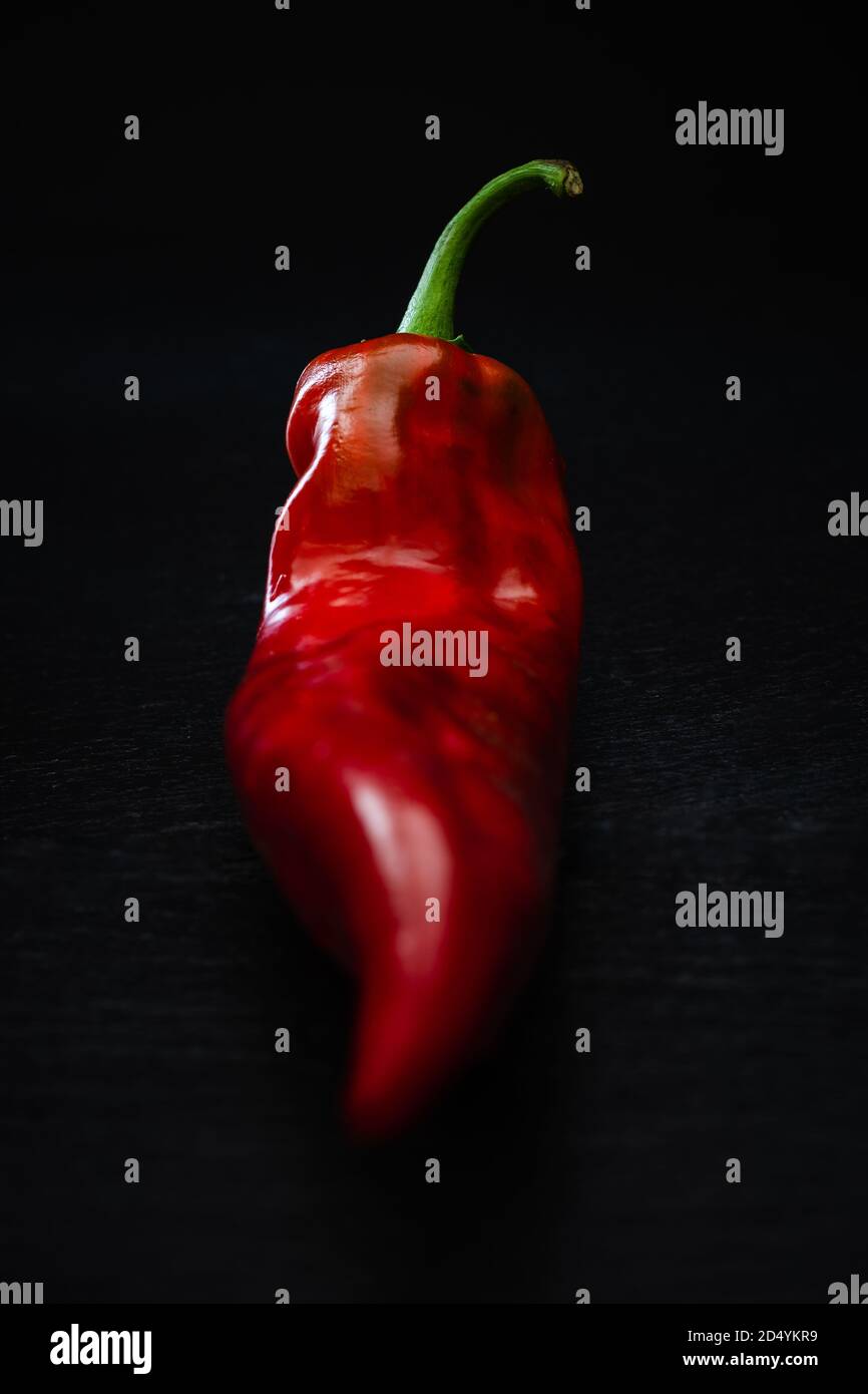 Red pointed peppers on black background - dark food Stock Photo - Alamy
