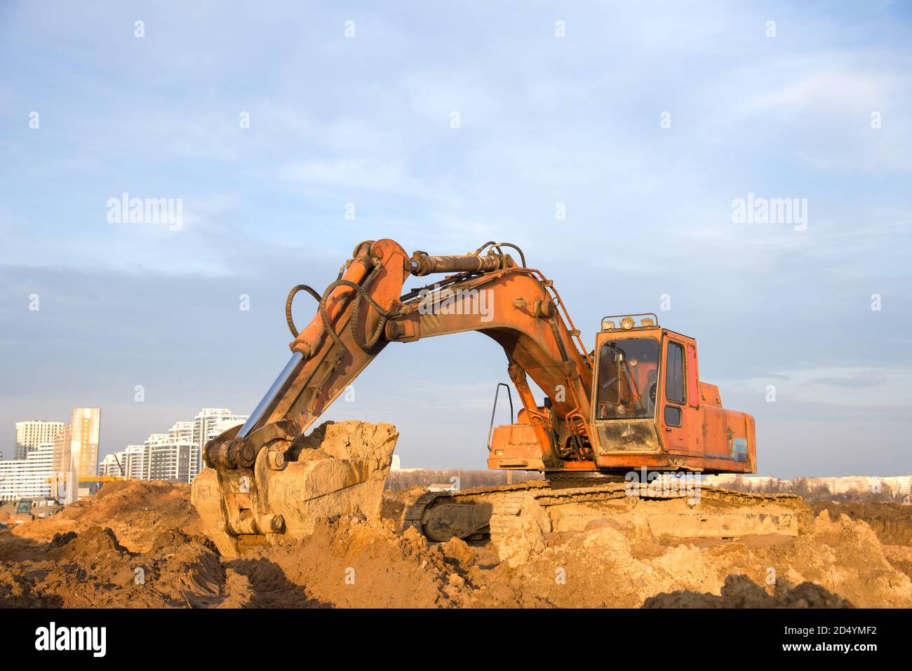 Excavator at earthworks on construction site. Backhoe loader digs a pit ...