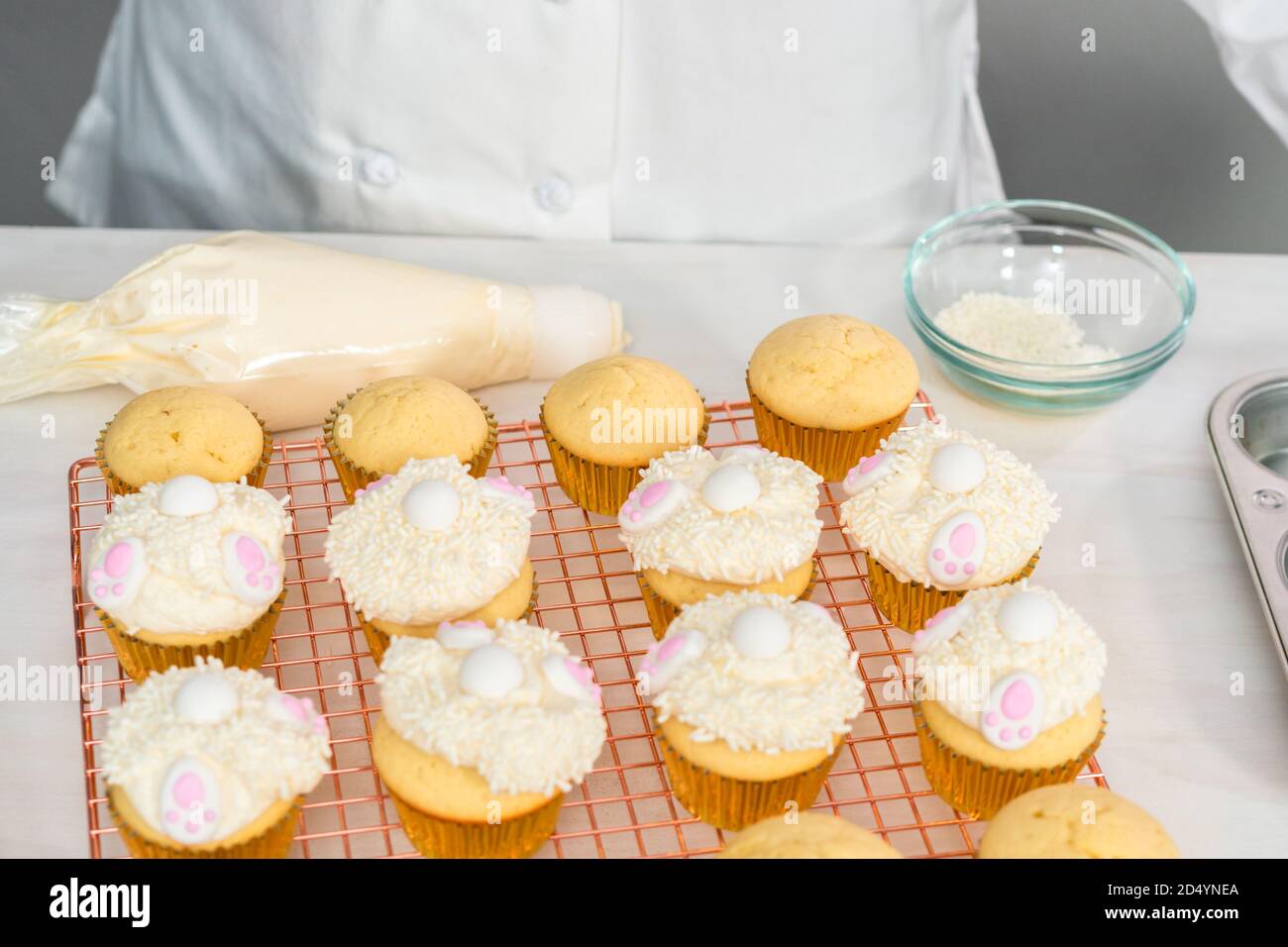 Decorating vanilla cupcakes with a white buttercream icing and bunny ...