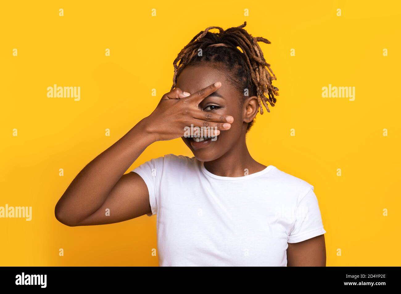 Cheerful african american lady playing hide and seek on yellow Stock ...