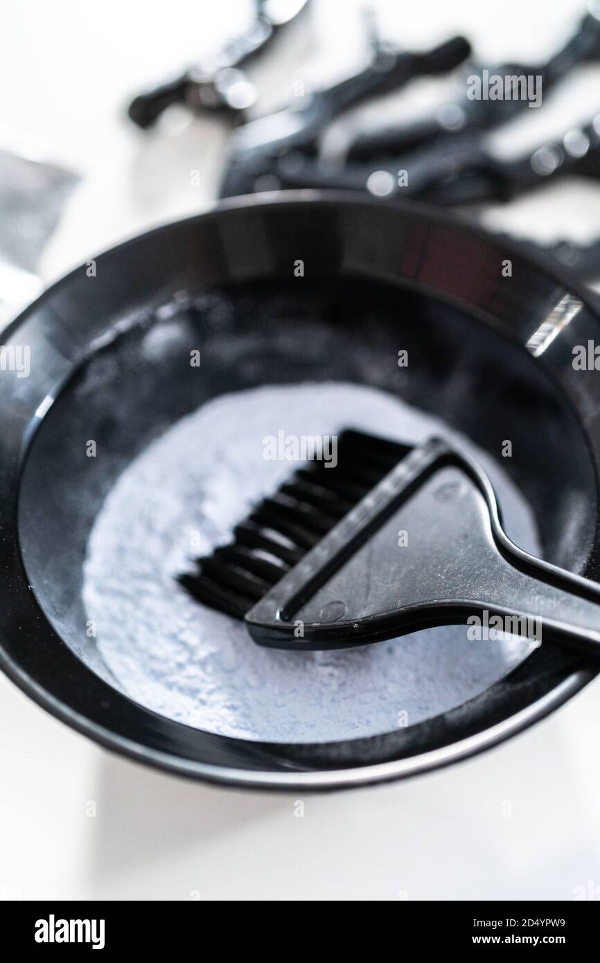Hair color dye powder in a black plastic mixing bowl on a white ...