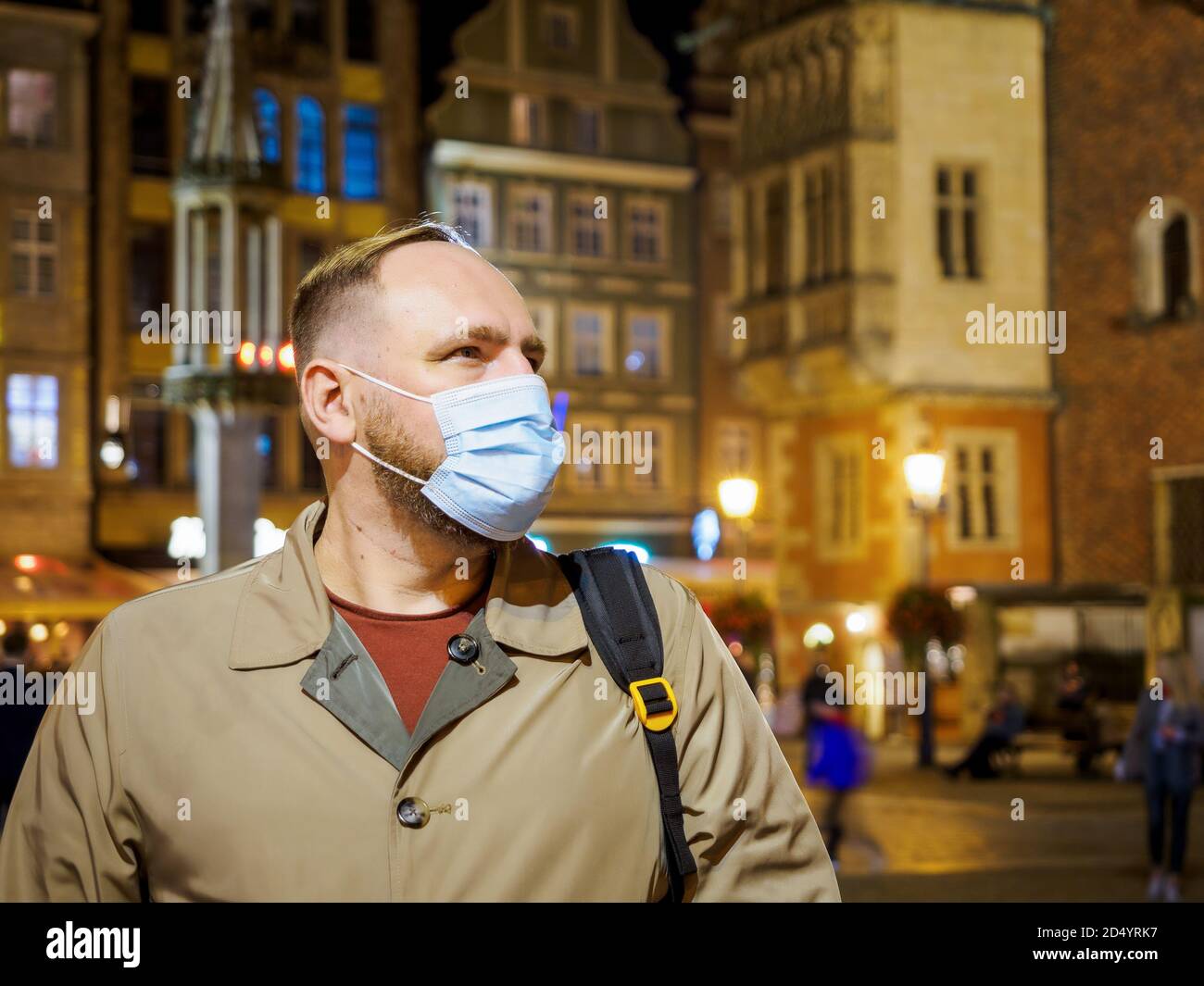 Adult man wearing mask walking in a night european city. Mask is a ...