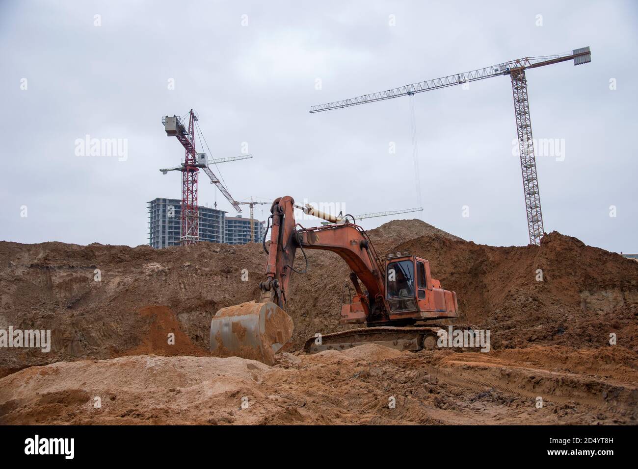 Red excavator digg trench for laying sewer pipes and main reticulation ...