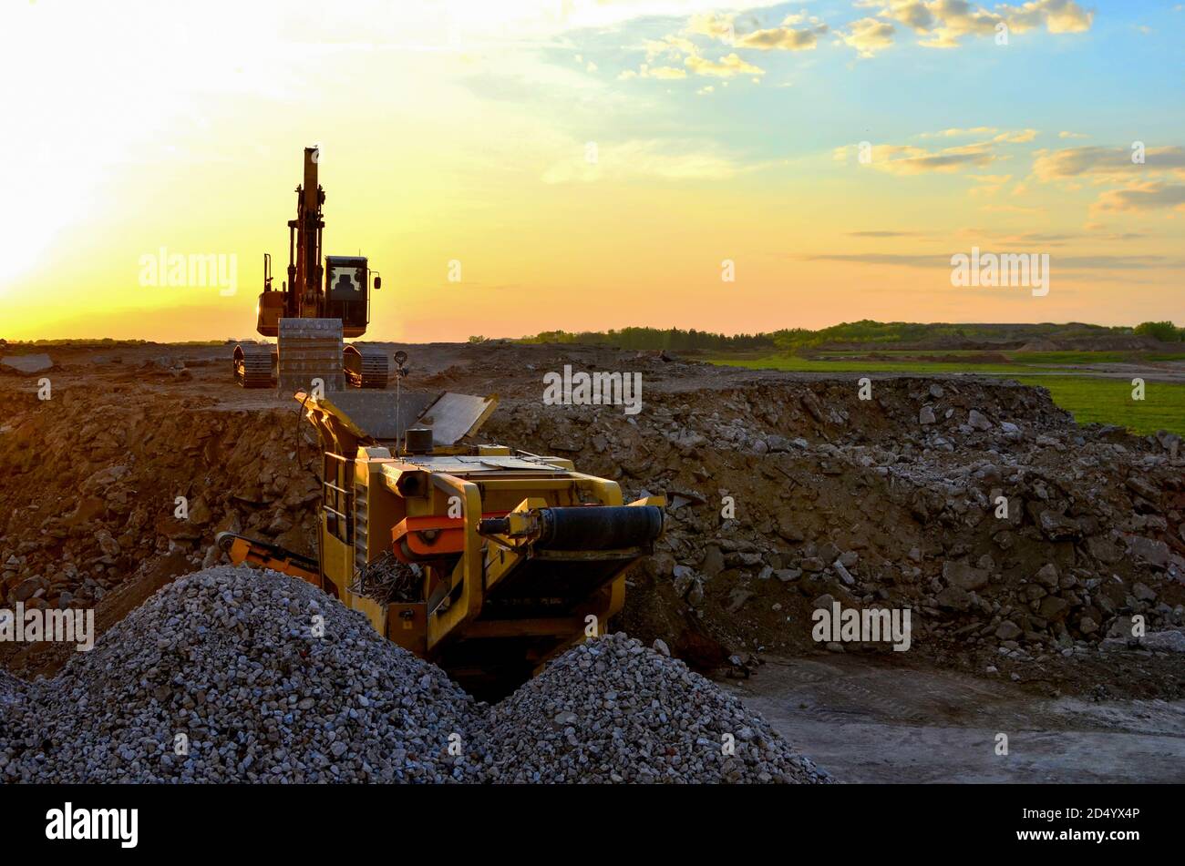 Excavator in a mining quarry at sunset. Mobile Stone crusher machine by ...
