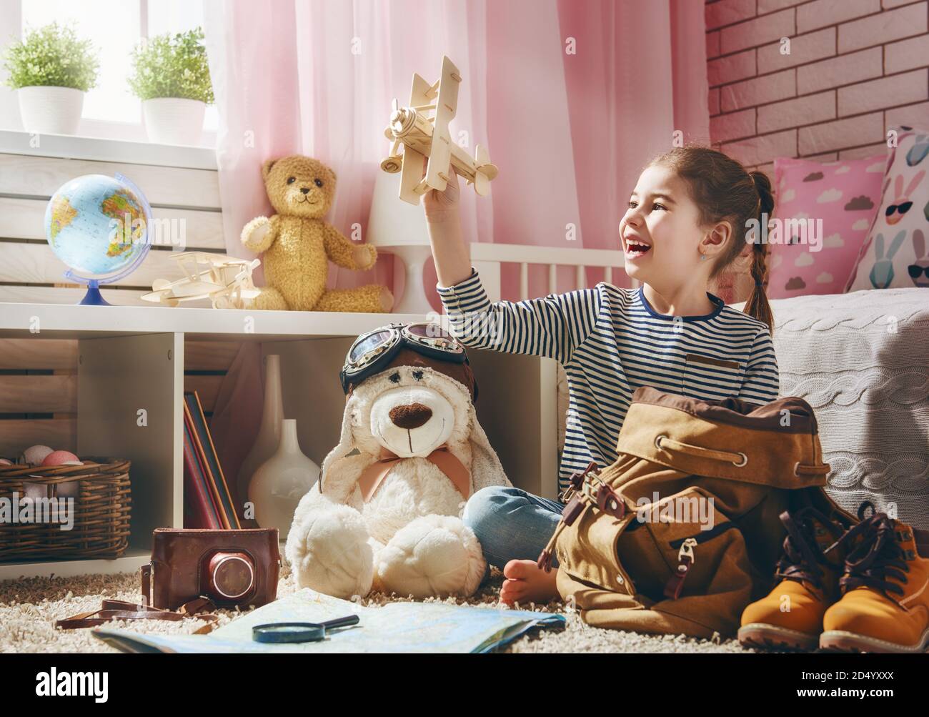 Happy child is getting ready for the journey. Girl is packing her bags ...