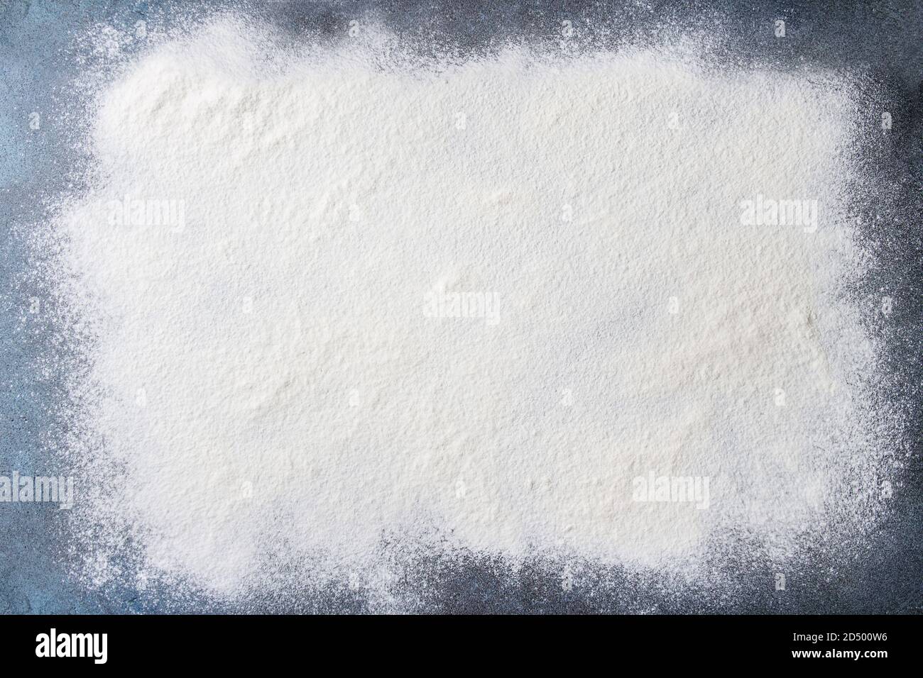 Sifted wheat flour over dark blue texture surface. Food background ...