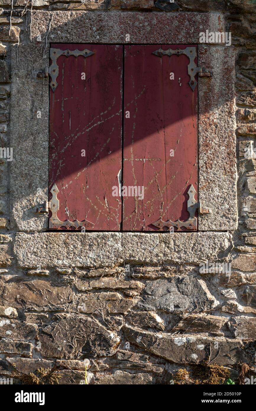 Red wooden shuttered Spanish window with a stone surround set into ...