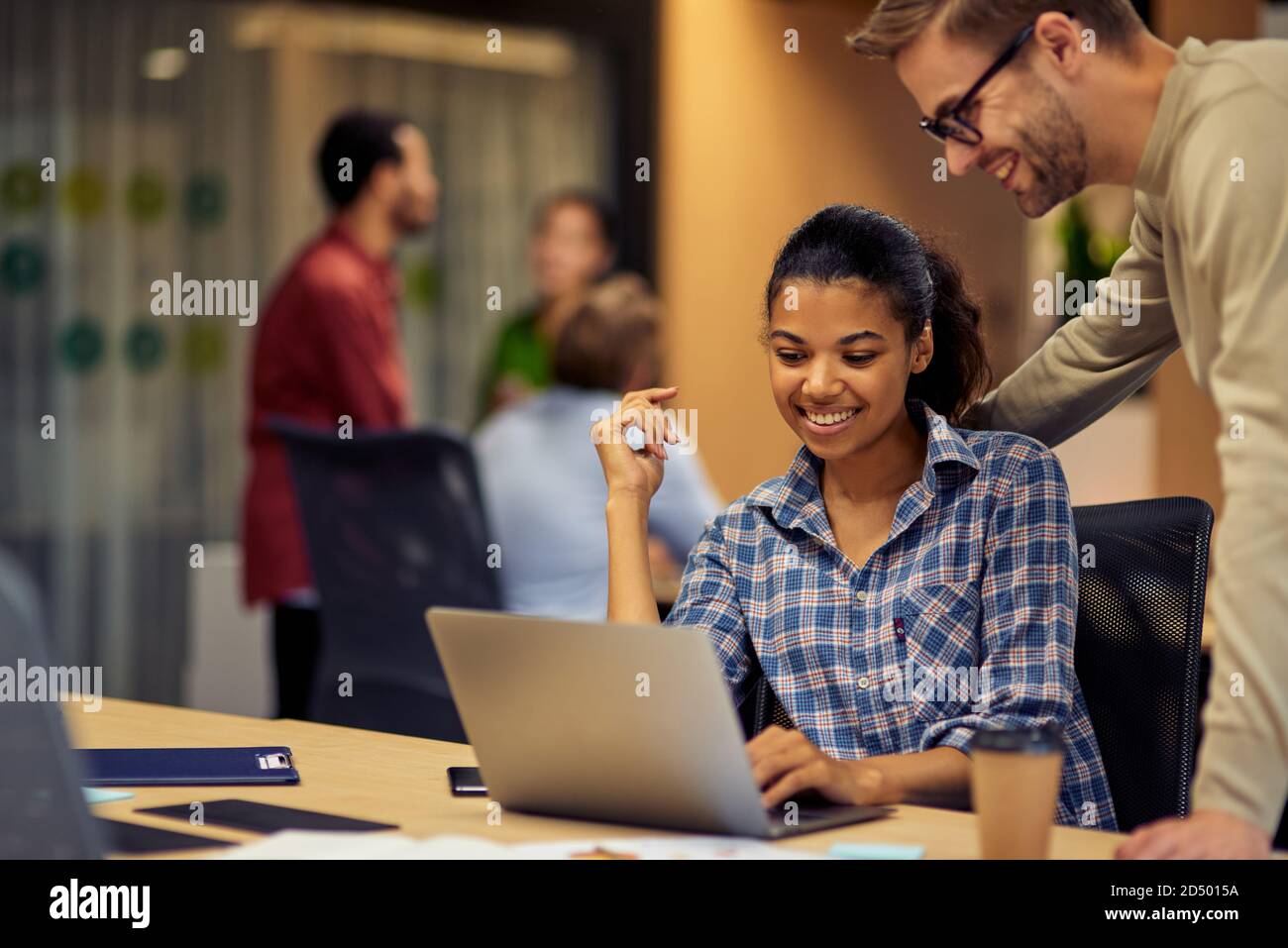 Young cheerful caucasian man helping female coworker with computer work ...