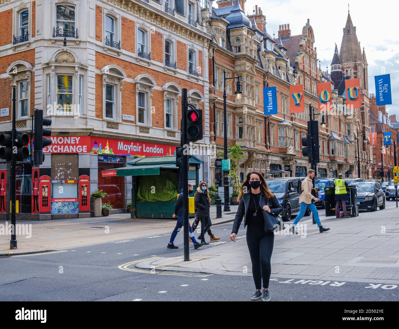 Lady with face mask crosses Oxford St at Duke St. Signs over street say ...