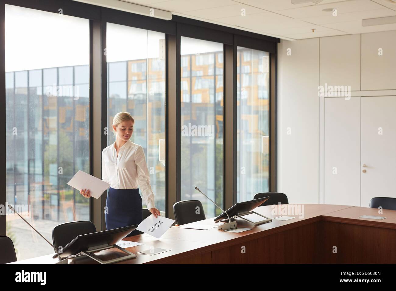 Wide angle portrait of blonde female secretary laying out documents on ...