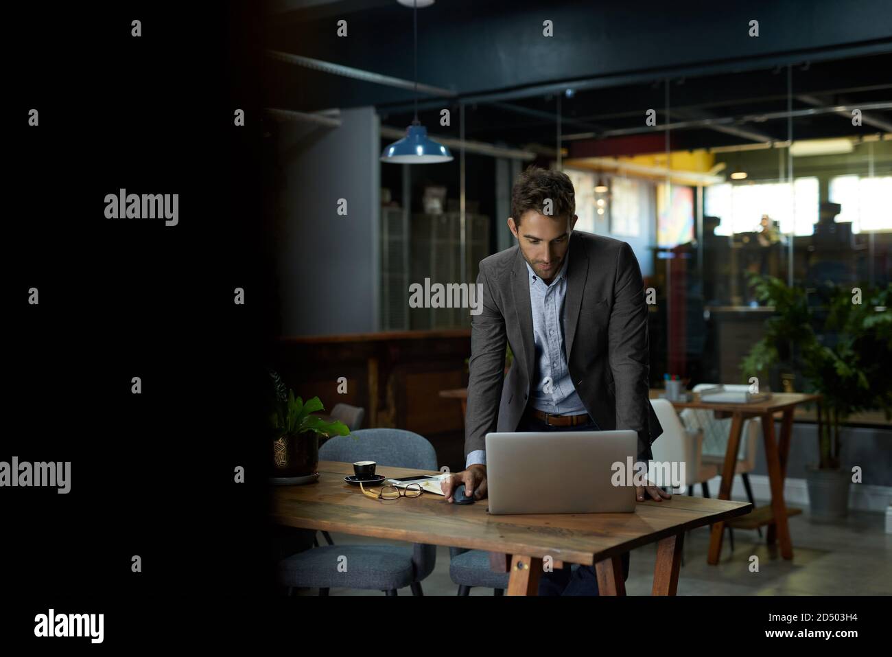 Businessman leaning over his office desk working on a laptop Stock ...