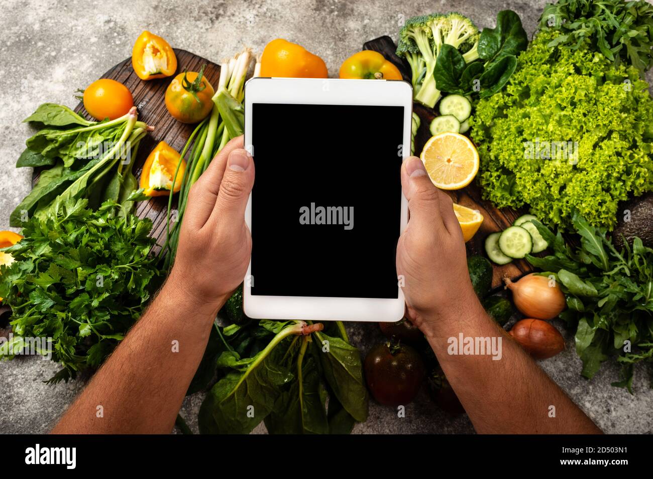 Male hands are holding the tablet computer with blank screen over fresh ...