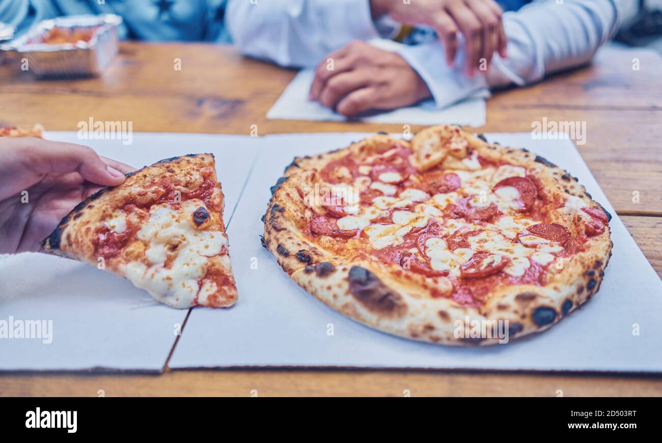 People's hands pick up pizza on a table in an outdoor market Stock ...