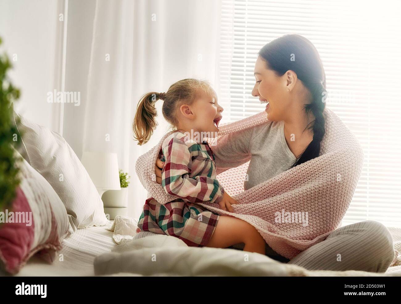 A nice baby girl and her mother enjoy sunny morning. Good time at home ...