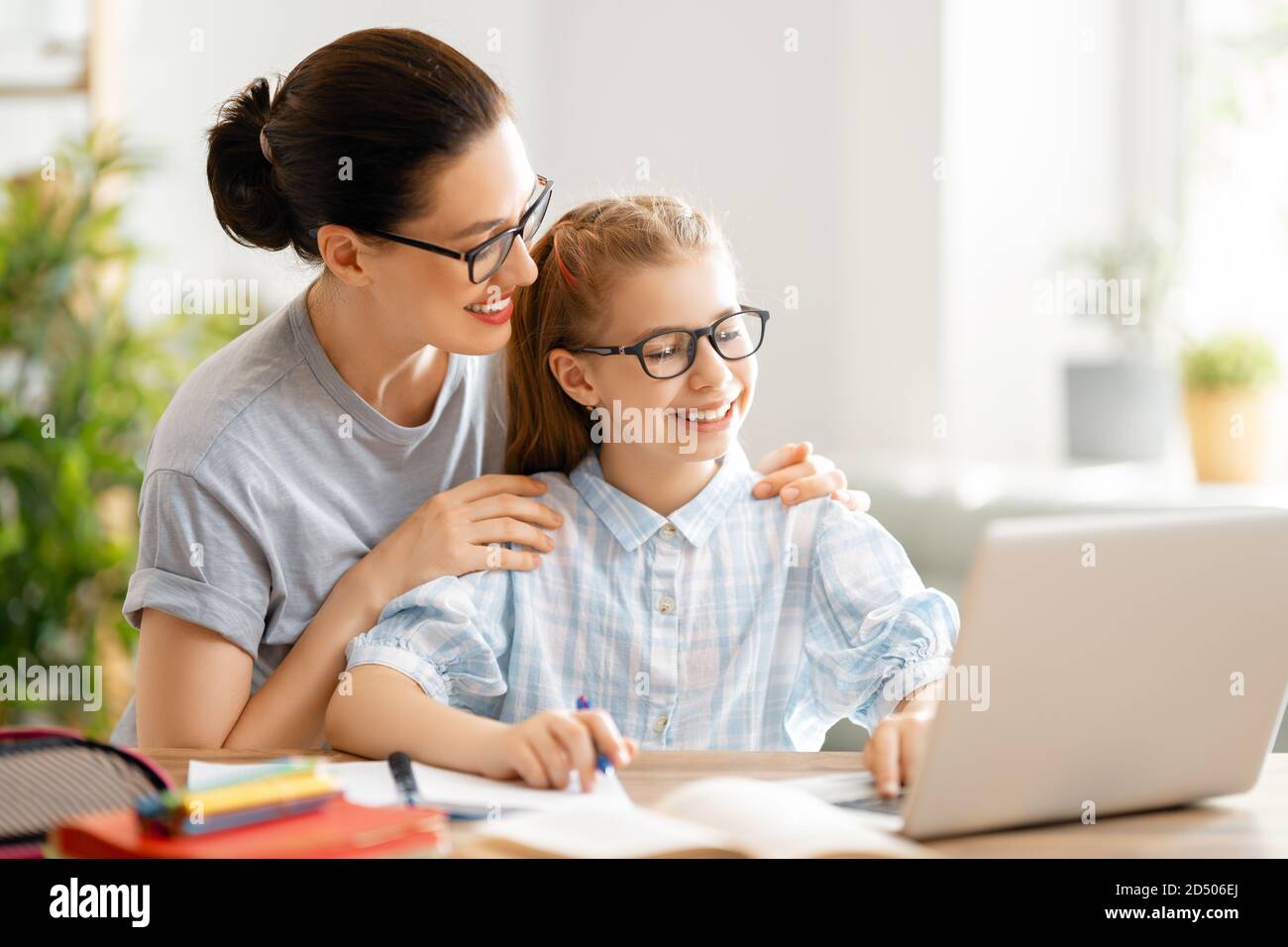 Back to school. Happy child and adult are sitting at desk. Girl doing ...
