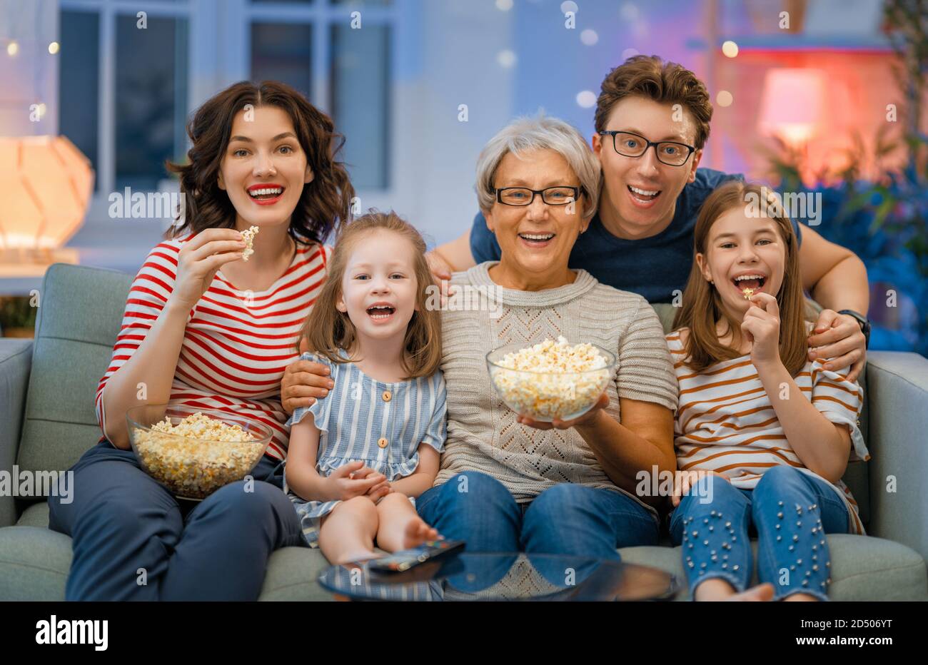 Happy family watching projector, TV, movies with popcorn in the evening ...