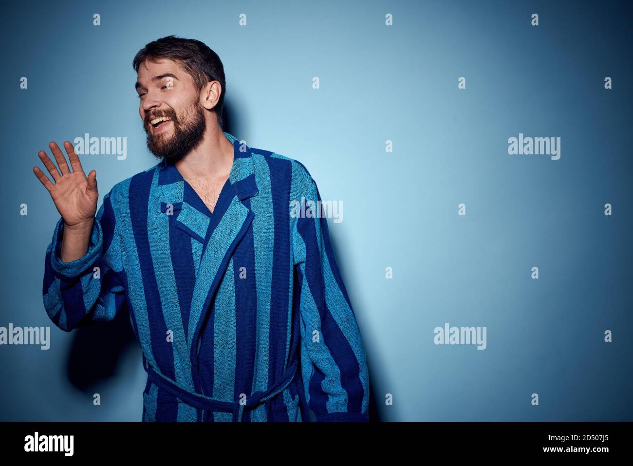 A man in a blue robe on a light background gestures with his hands ...
