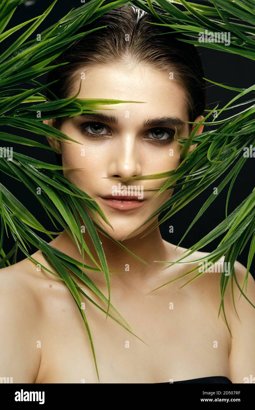Woman's face among green leaves of a palm tree nature Stock Photo - Alamy