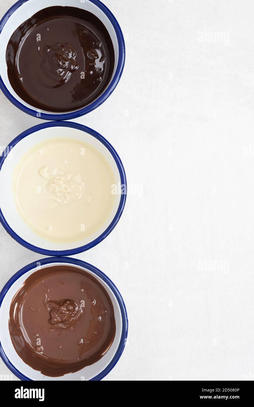 Three types of melted chocolate in bowls. Dark chocolate, milk ...