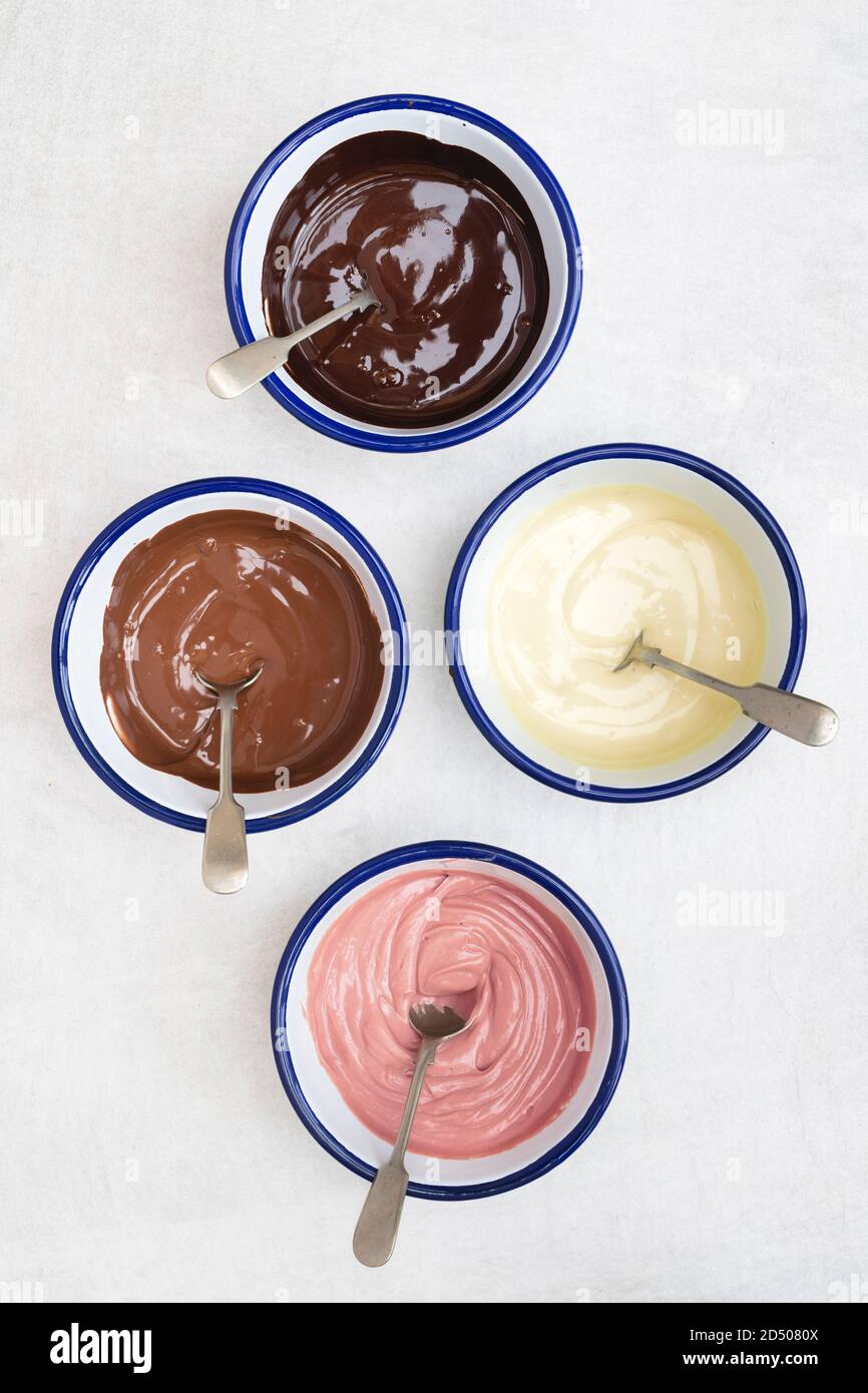 Four types of melted chocolate in bowls. Dark chocolate, milk chocolate ...