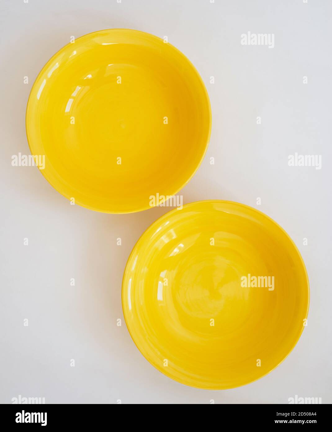Two yellow plates on a white background Stock Photo - Alamy