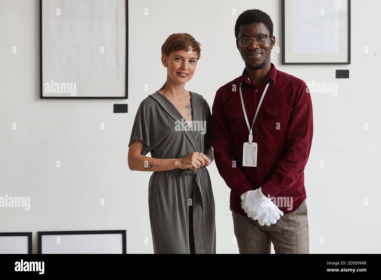 Portrait of female art gallery manager posing with African-American ...