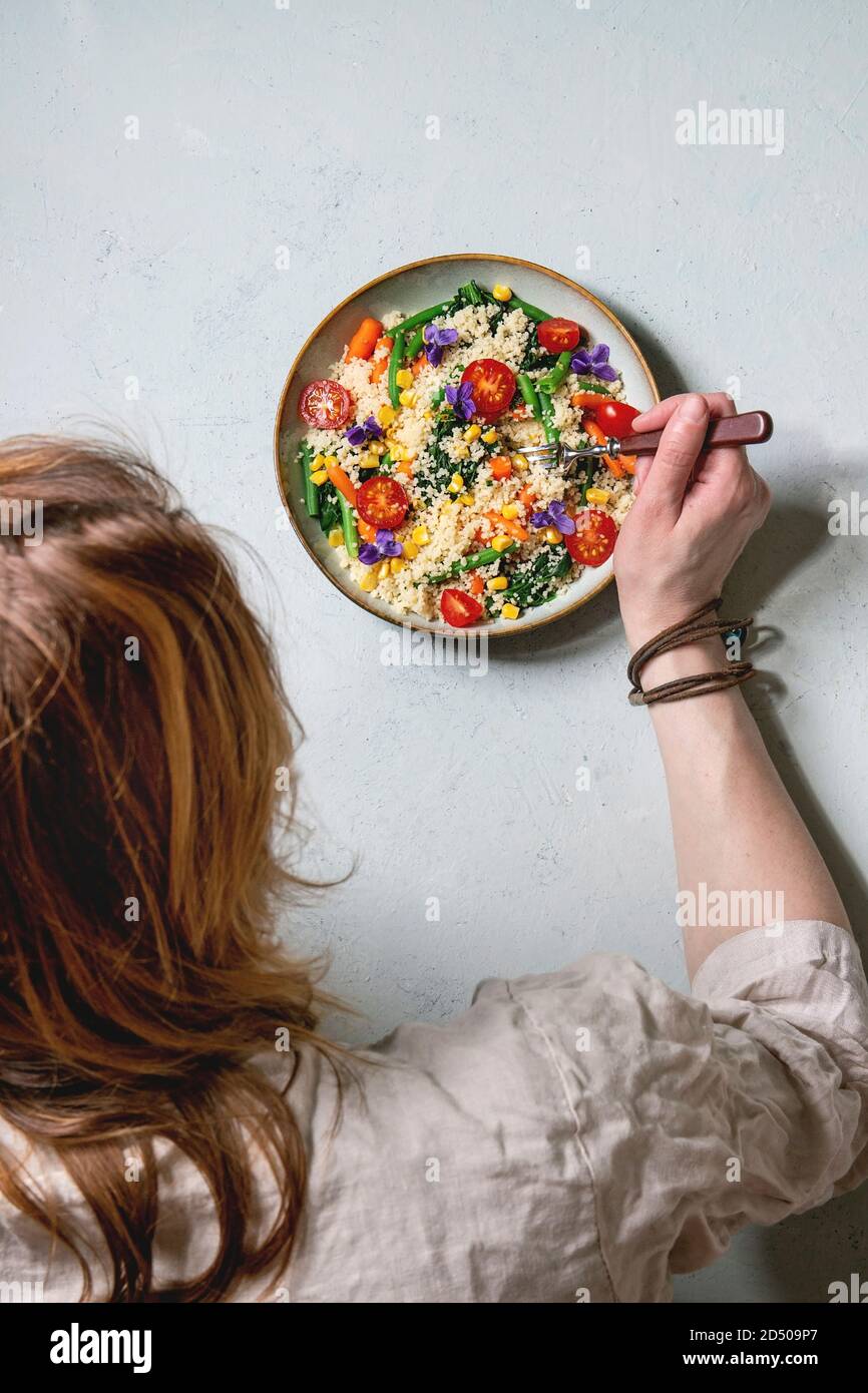 Woman eating Couscous salad with parboiled vegetables baby carrots ...