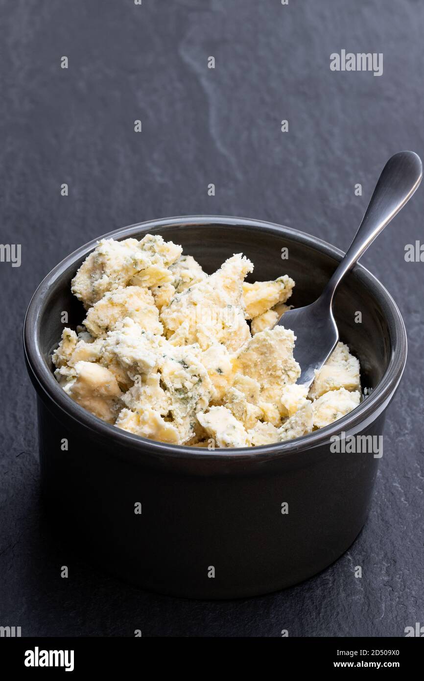 Potted aged Blue stilton cheese on black stone background Stock Photo ...