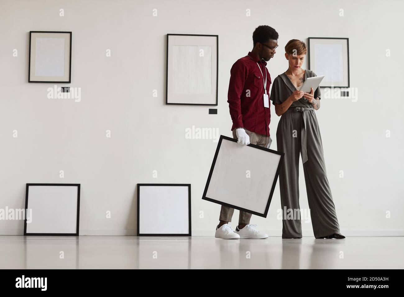 Graphic full length portrait of female art gallery manager using ...