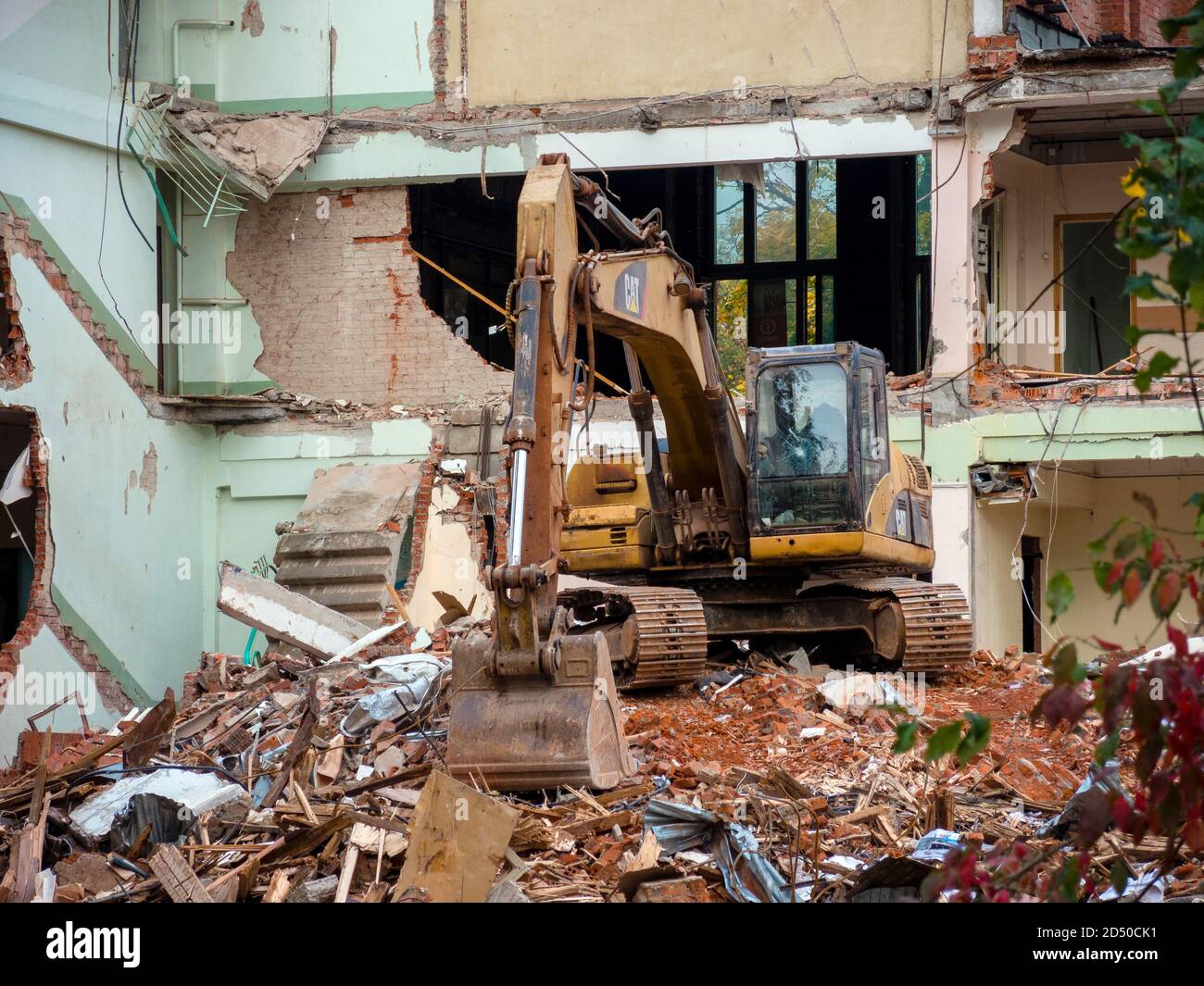 Yellow excavator at demolition site, destroyed old building at ...