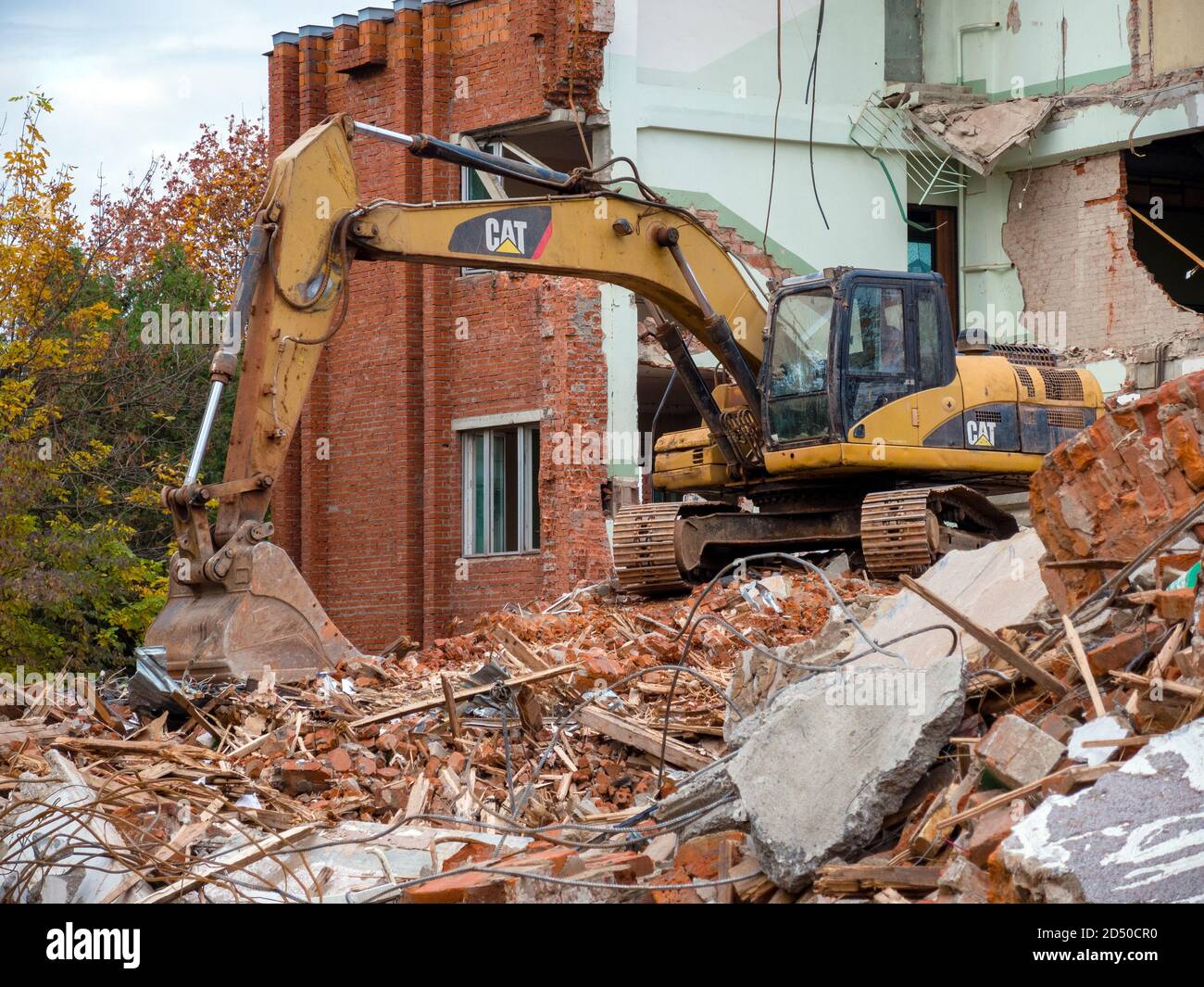 Yellow excavator at demolition site, destroyed old building at ...