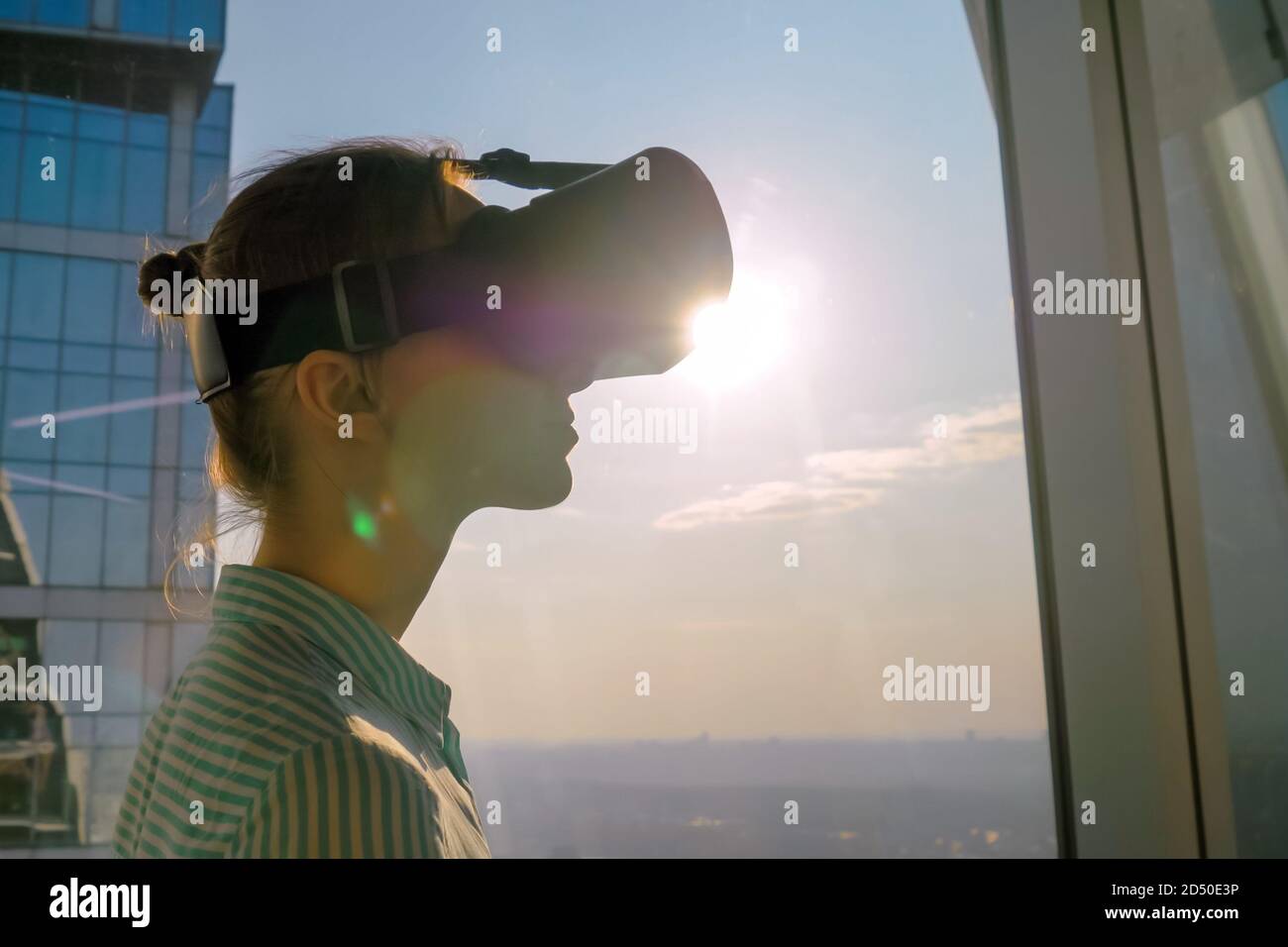 Woman using virtual reality headset and looking around against view on ...