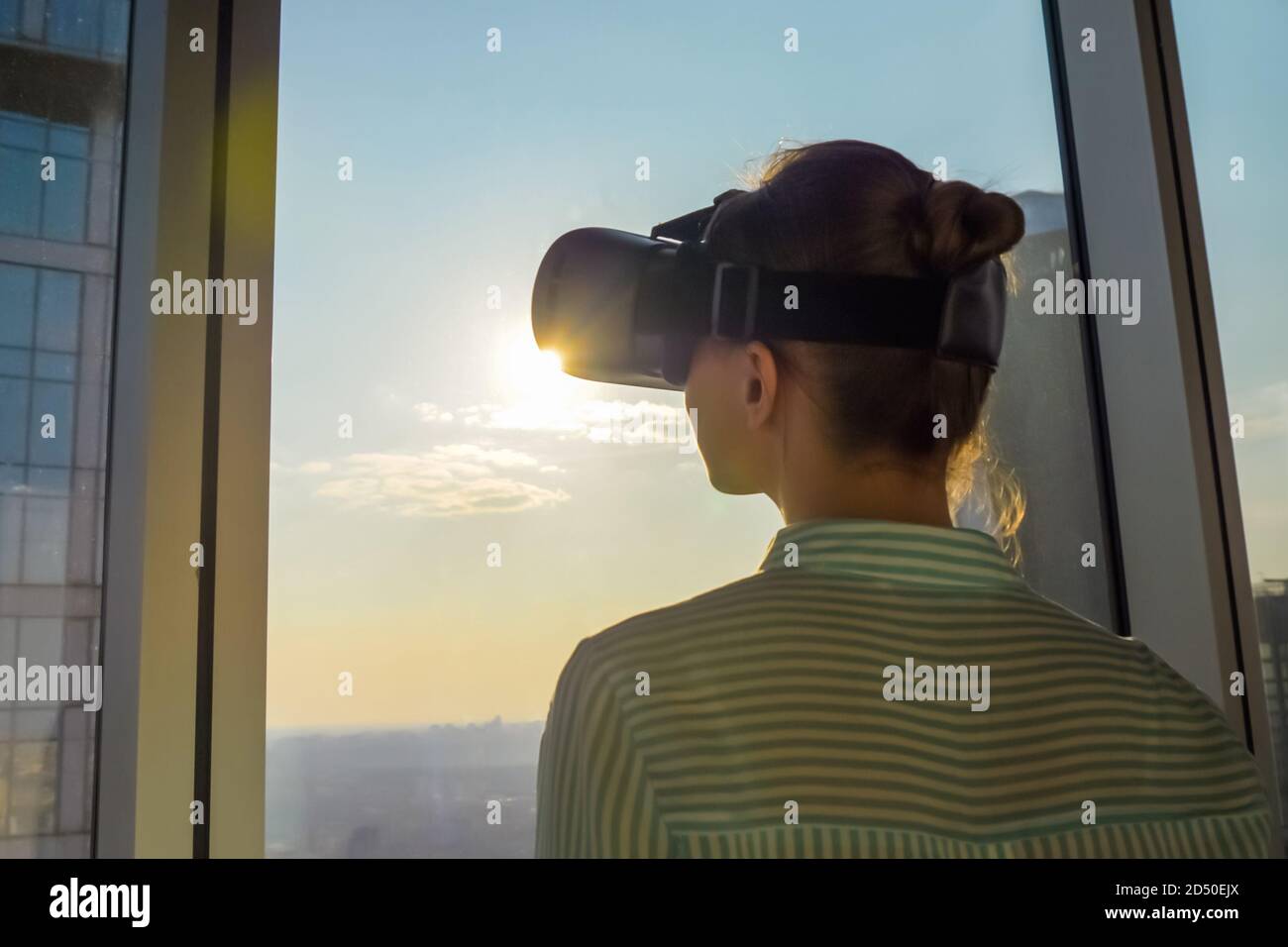 Woman using virtual reality headset and looking around against view on ...