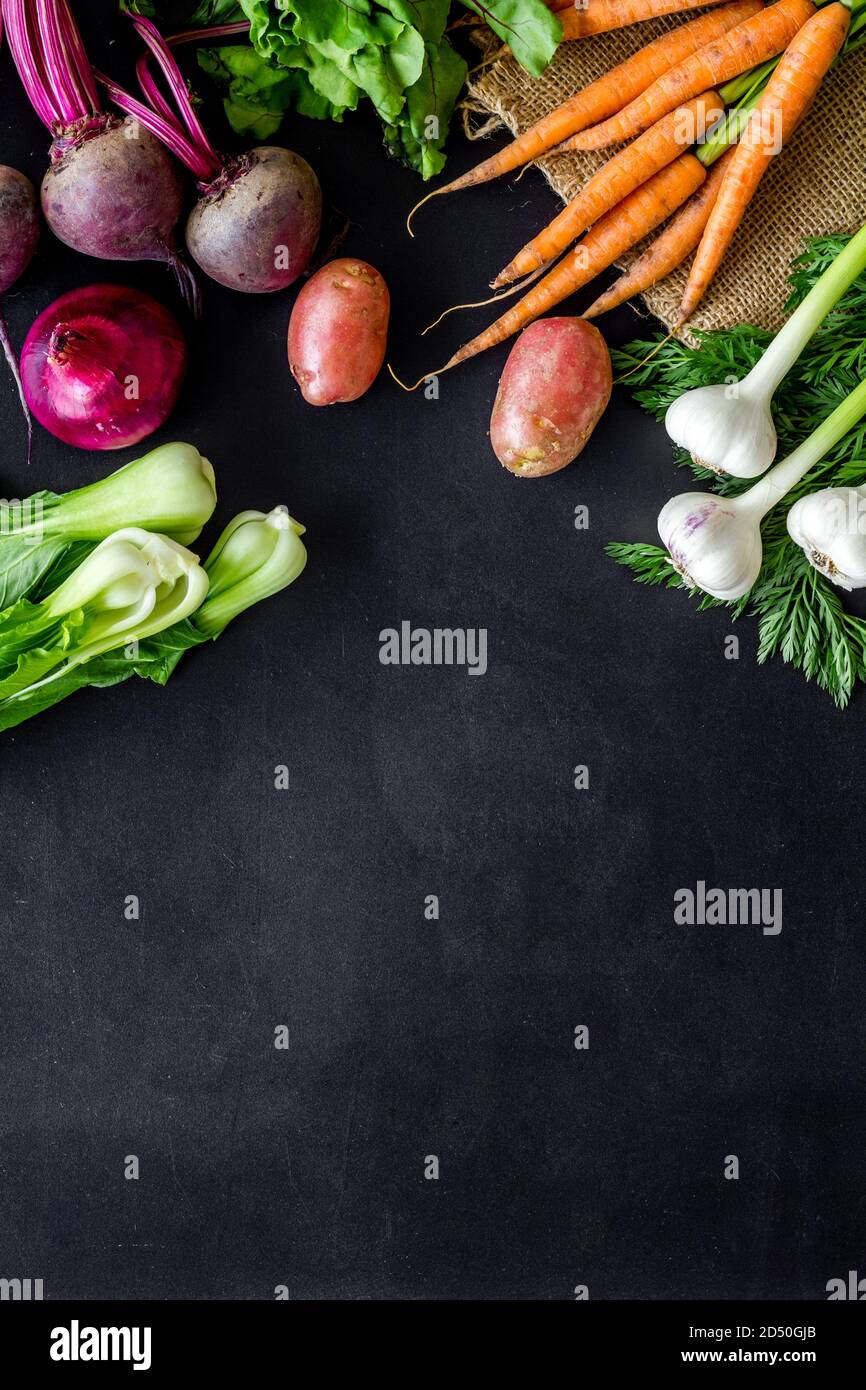 Flat lay of fresh vegetables and greenery on black table top-down copy ...