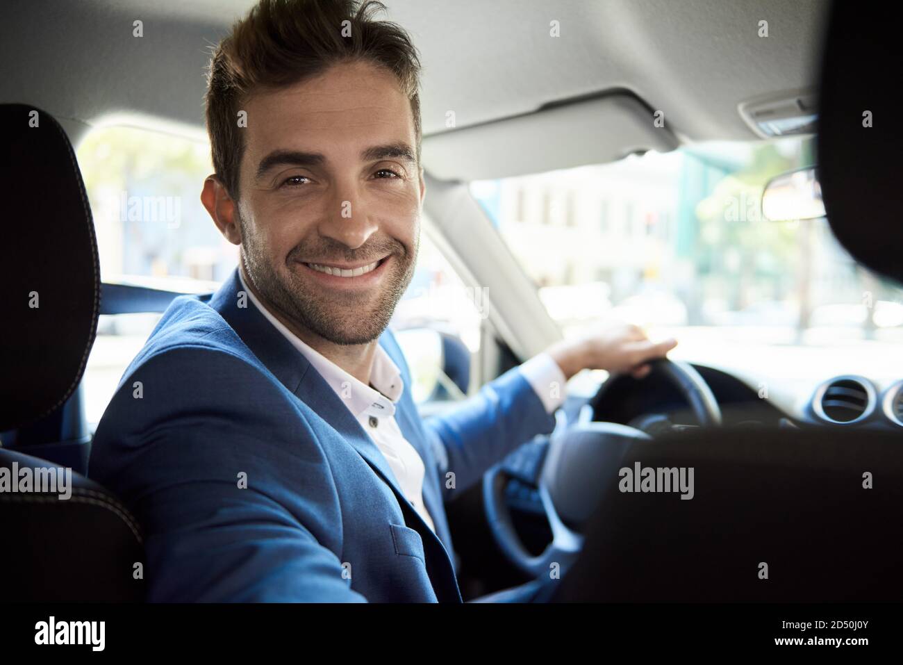 Smiling young driver looking over his shoulder in his car Stock Photo ...